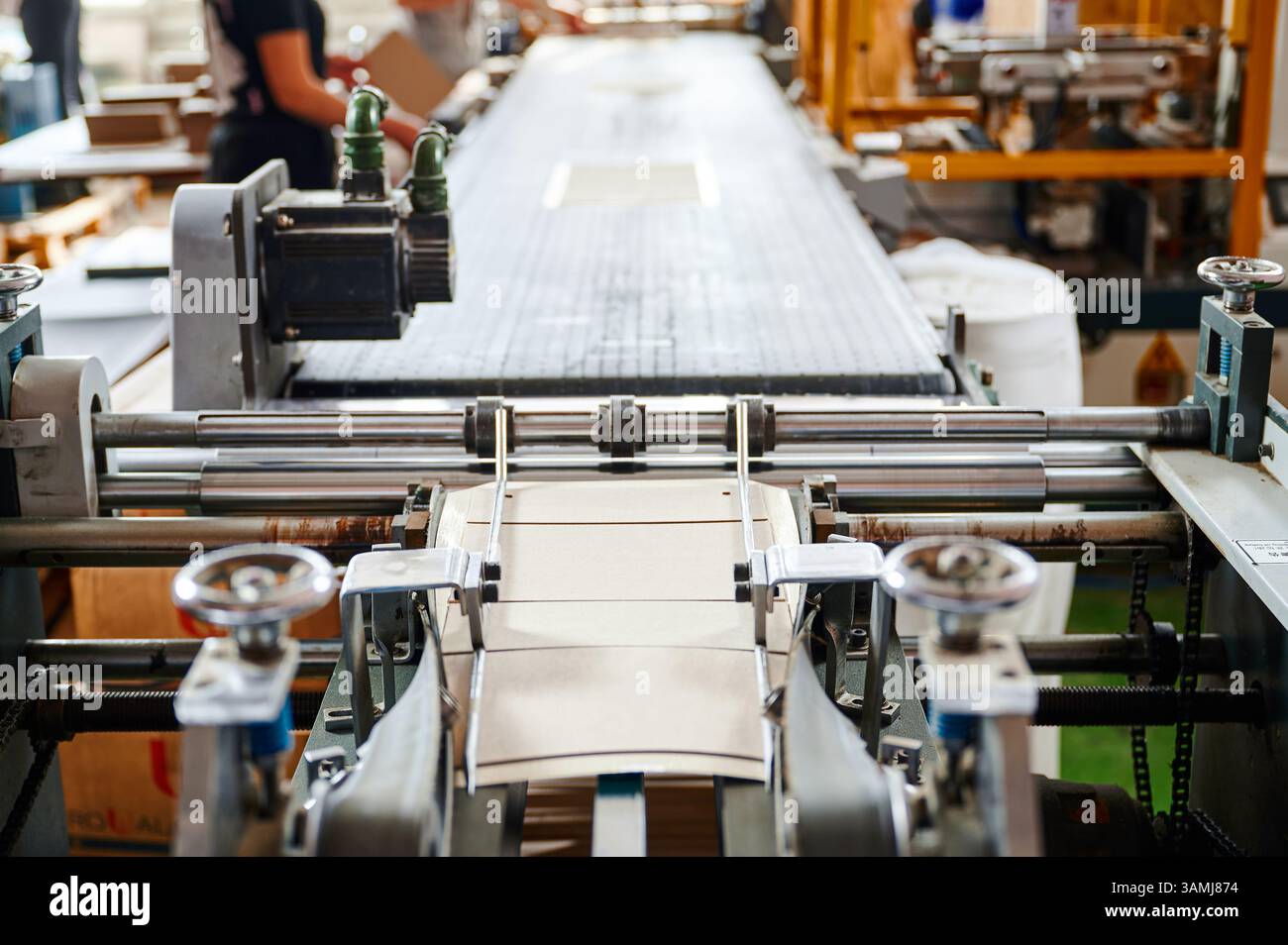 Machine efficiently folds flaps of cardboard boxes in a busy packaging ...