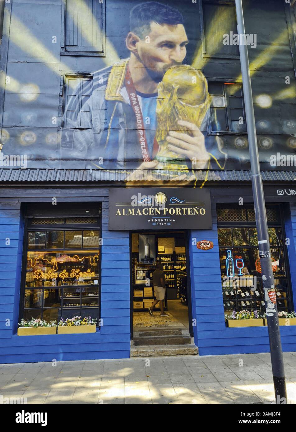 Shop front with a large mural of footballer Lionel Messi with trophy ...