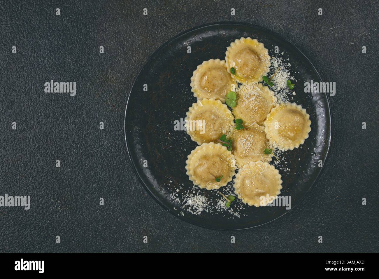 Fresh ravioli with cheese and microgreens, on a black plate, top view ...