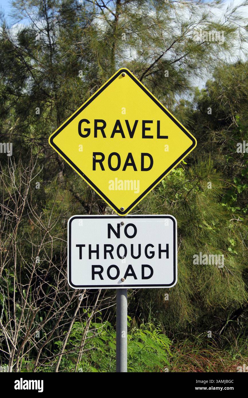 Yellow "Gravel Road" road sign and a white "No Through Road" sign with ...