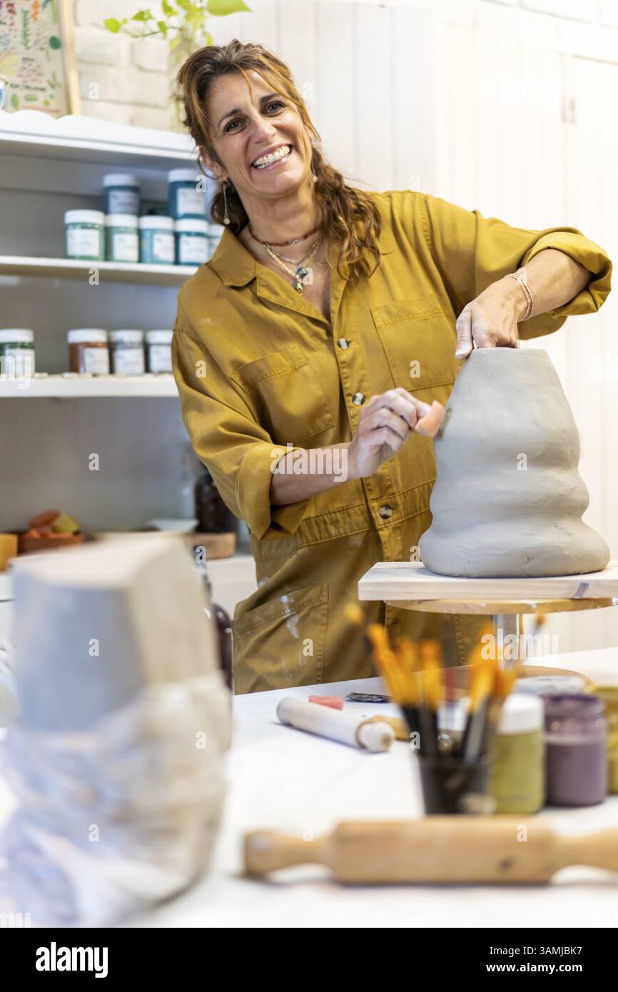 Happy artist molding clay in a vibrant workspace Stock Photo - Alamy