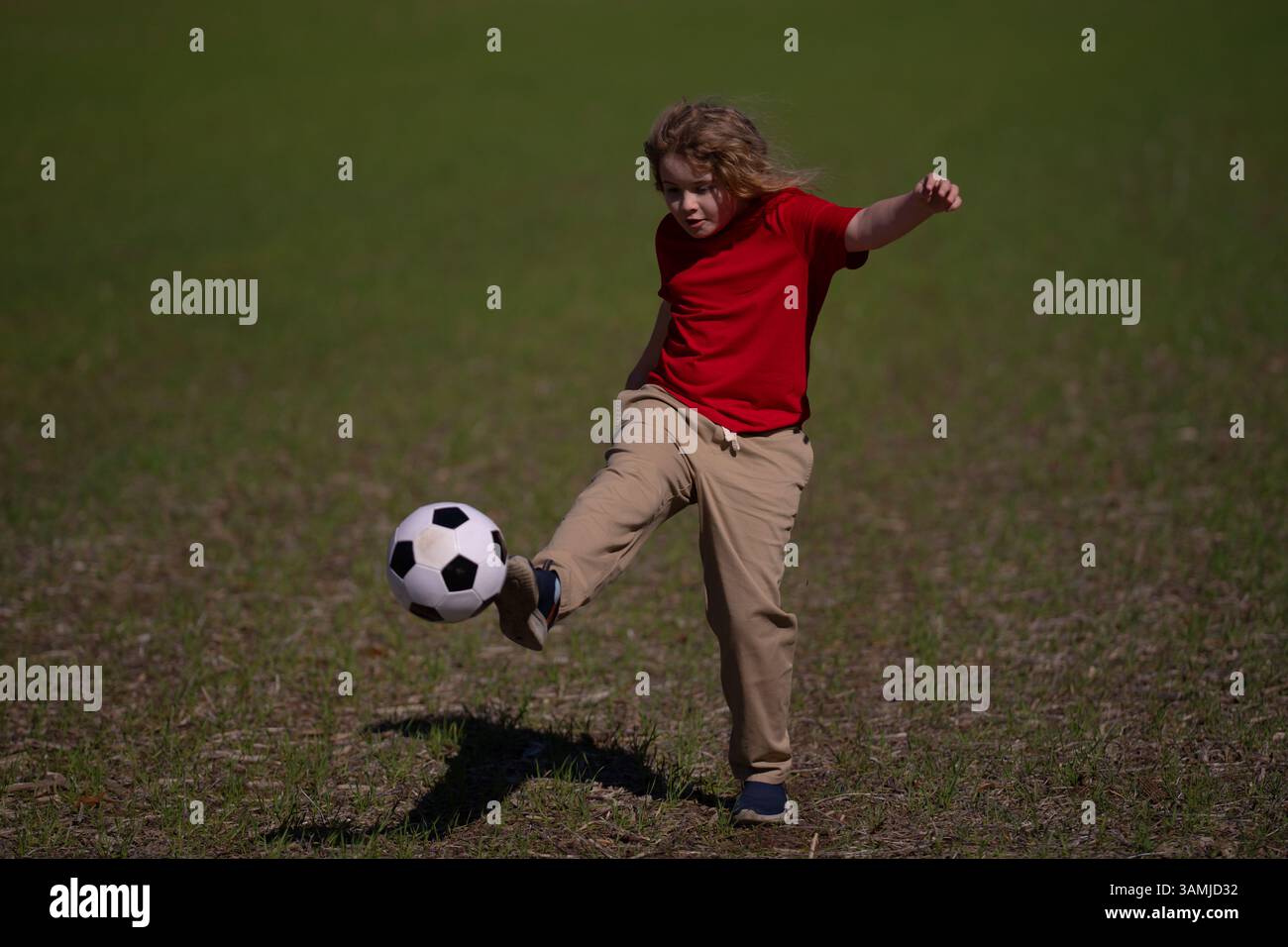 A child is playing football. A child kicks the soccer ball. Kids sport ...