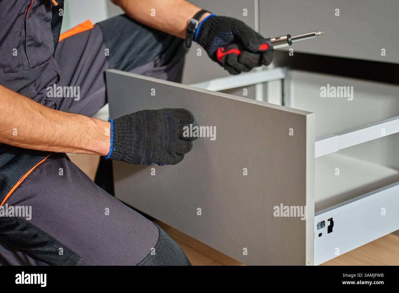 Man assembling kitchen drawer in modern cabinet using screwdriver ...