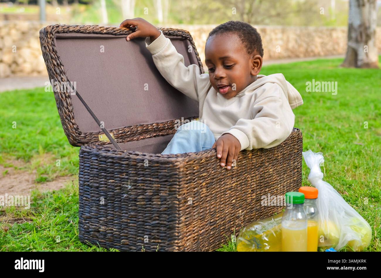 Happy african american toddler looking inside wicker basket during ...