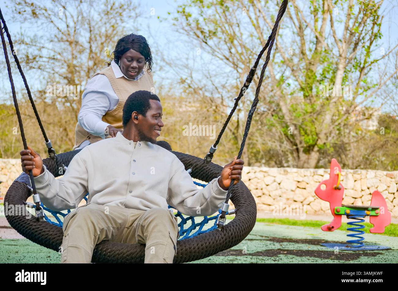 African american man and woman having fun swinging on nest swing in a ...