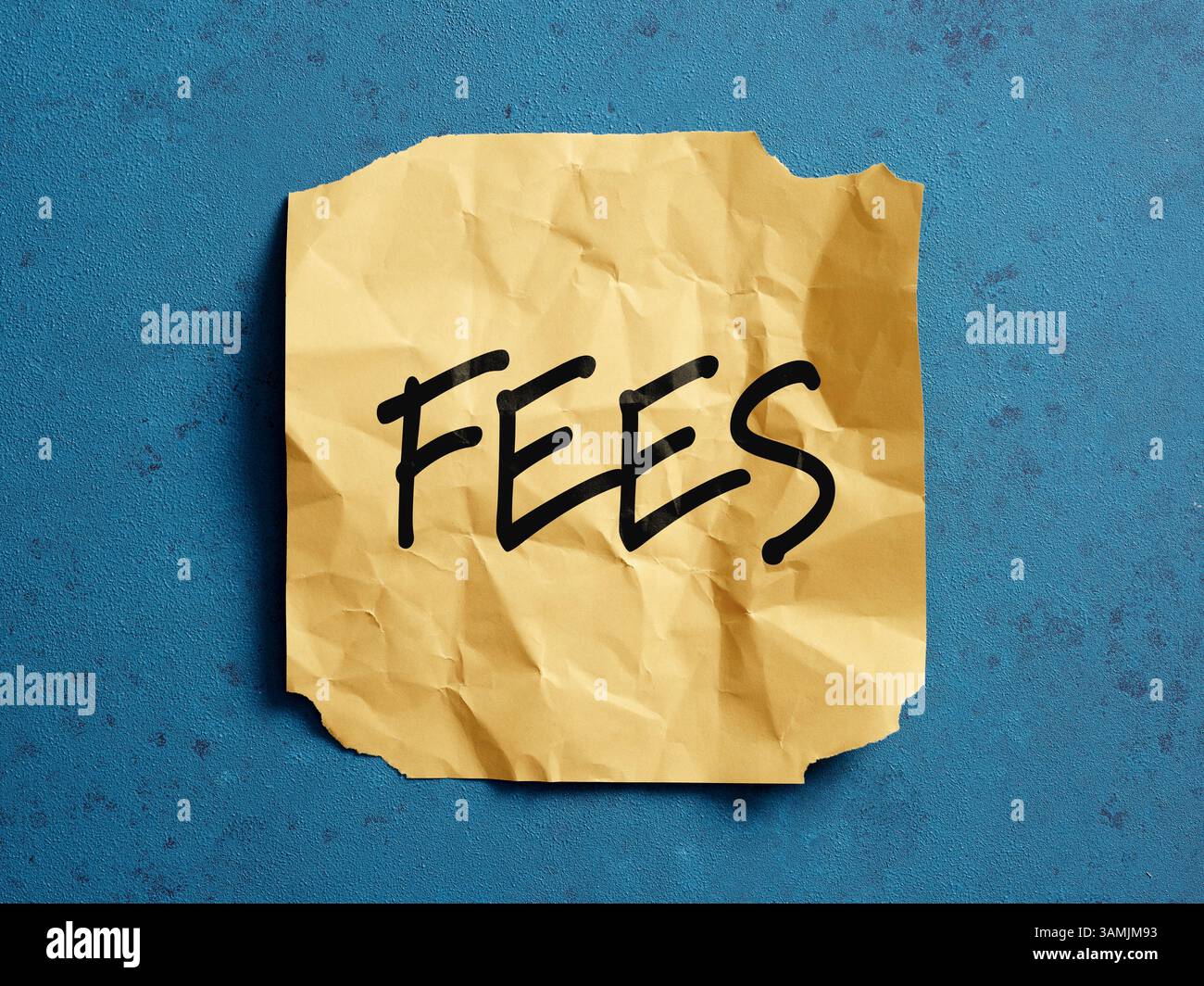 Fees written on crumpled yellow paper note on blue background ...