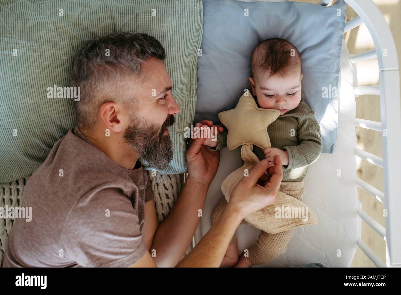 Father putting the baby to sleep, lying next to him in the crib Stock ...