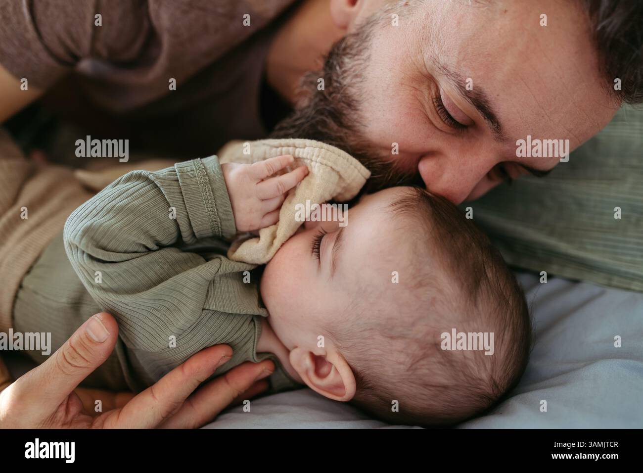 Father putting the baby to sleep, lying next to him in the crib Stock ...