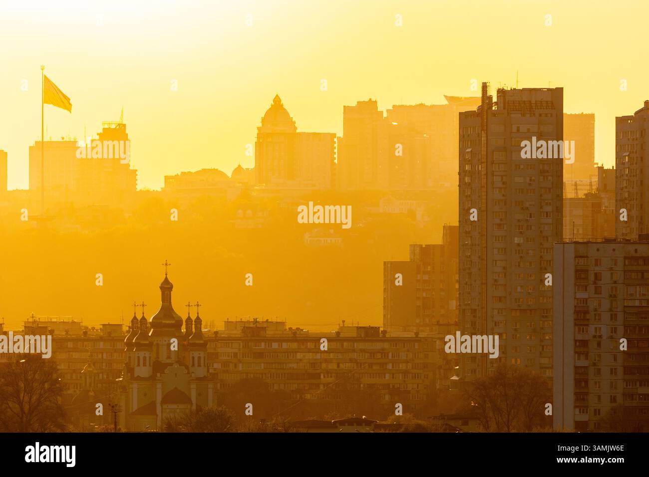 A dramatic sunset over the silhouetted skyline of Kyiv, with the sun ...