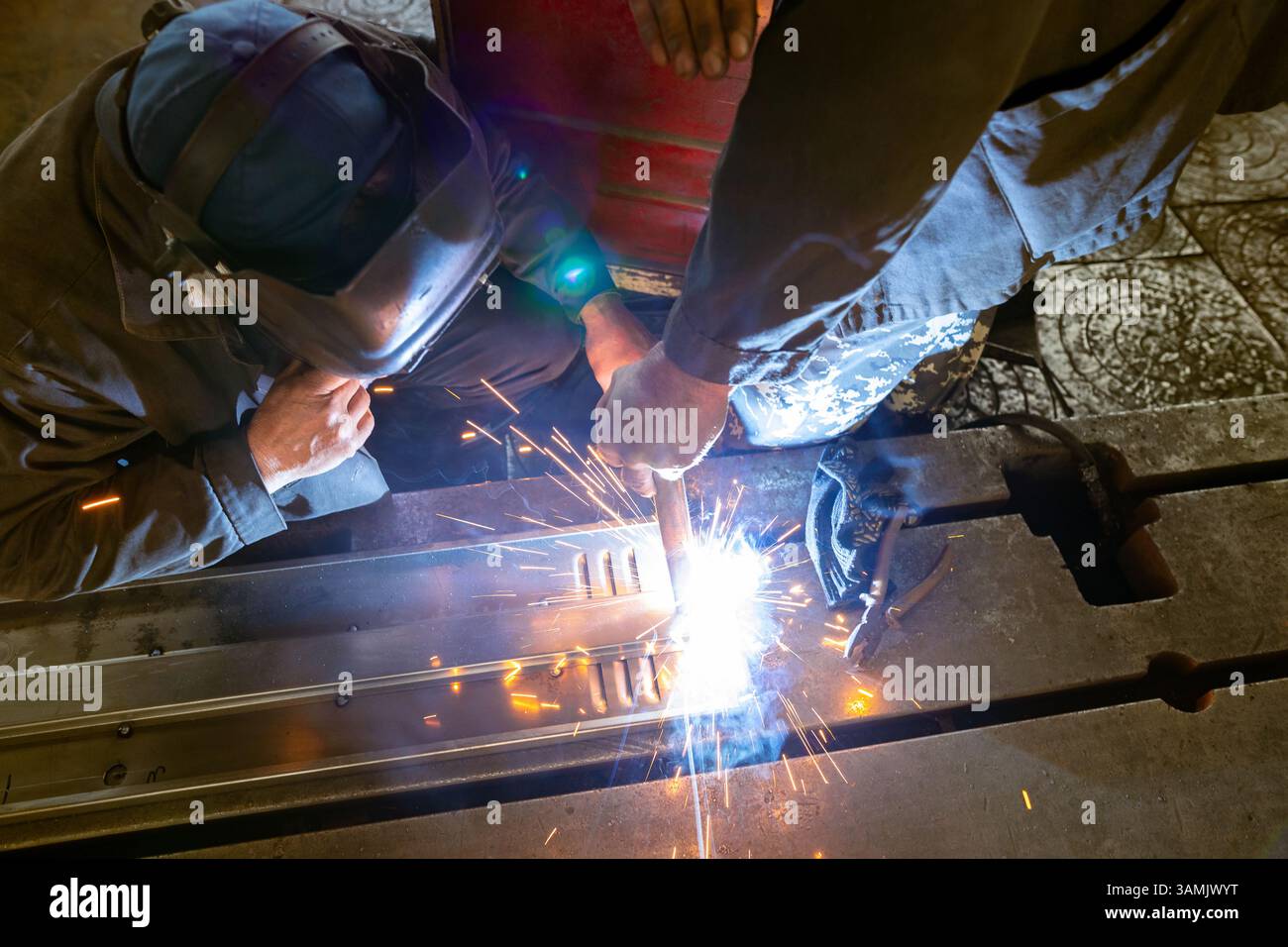 A welder, holding the automatic welding head, and an assistant, firmly ...