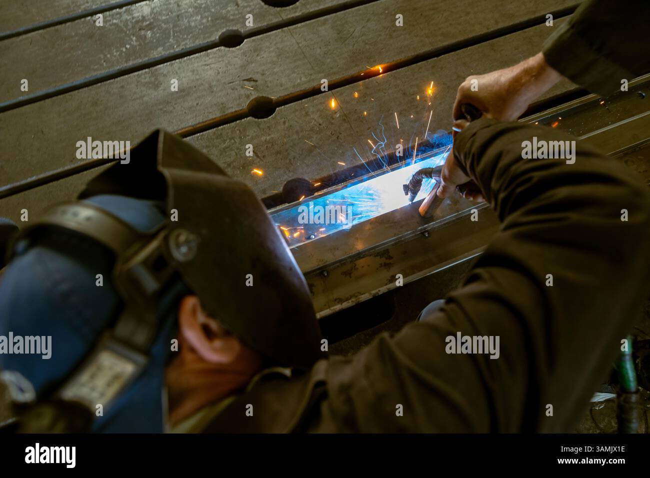 A welder, holding the automatic welding head, and an assistant, firmly ...