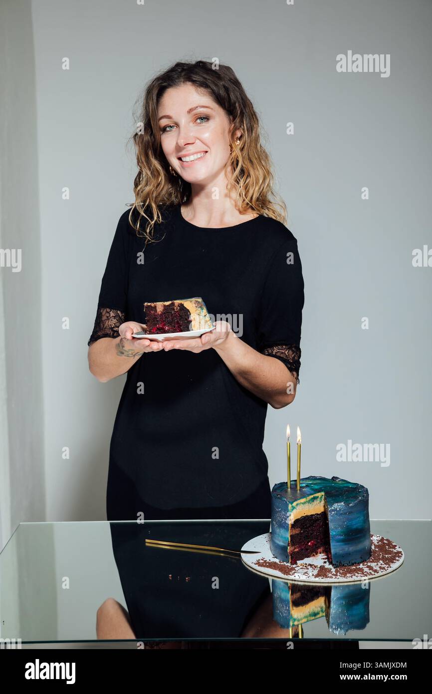 Beautiful woman cutting birthday cake and smiling Stock Photo - Alamy