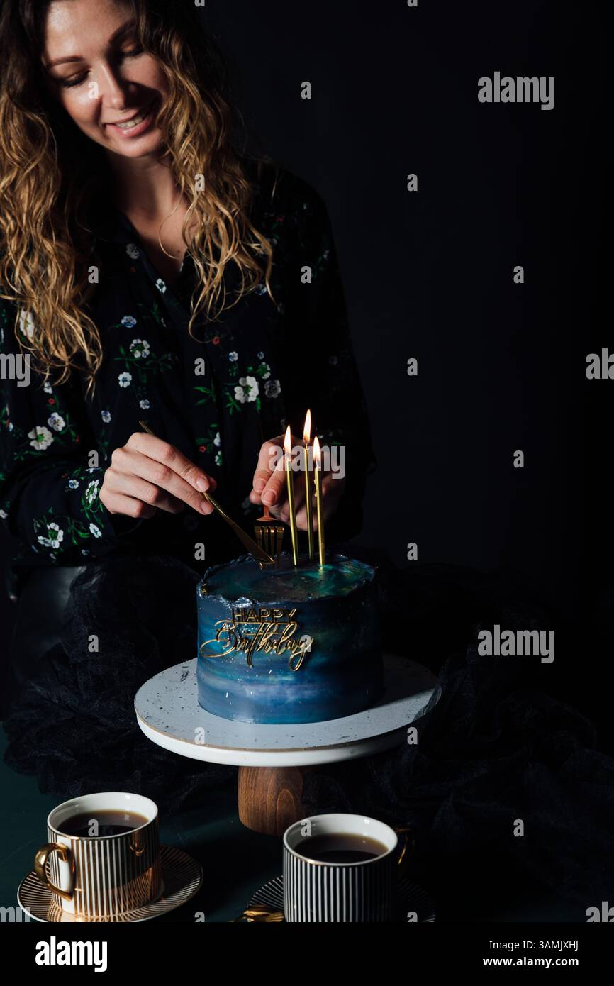 Beautiful woman cutting birthday cake and smiling Stock Photo - Alamy