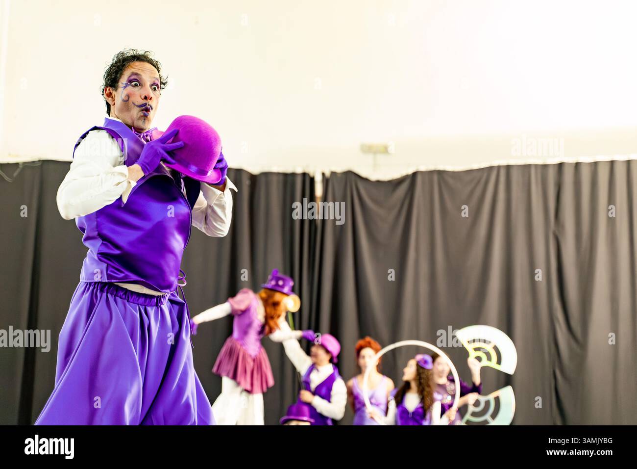 Comedian wearing purple clothes and bowler hat performing a funny ...