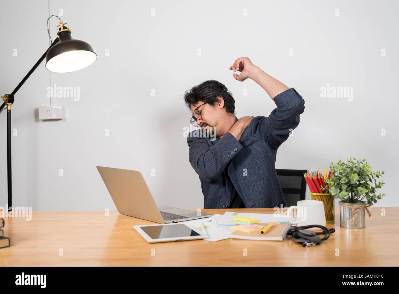 Businessman works on laptop, Stretch fingers to relieve fatigue ...
