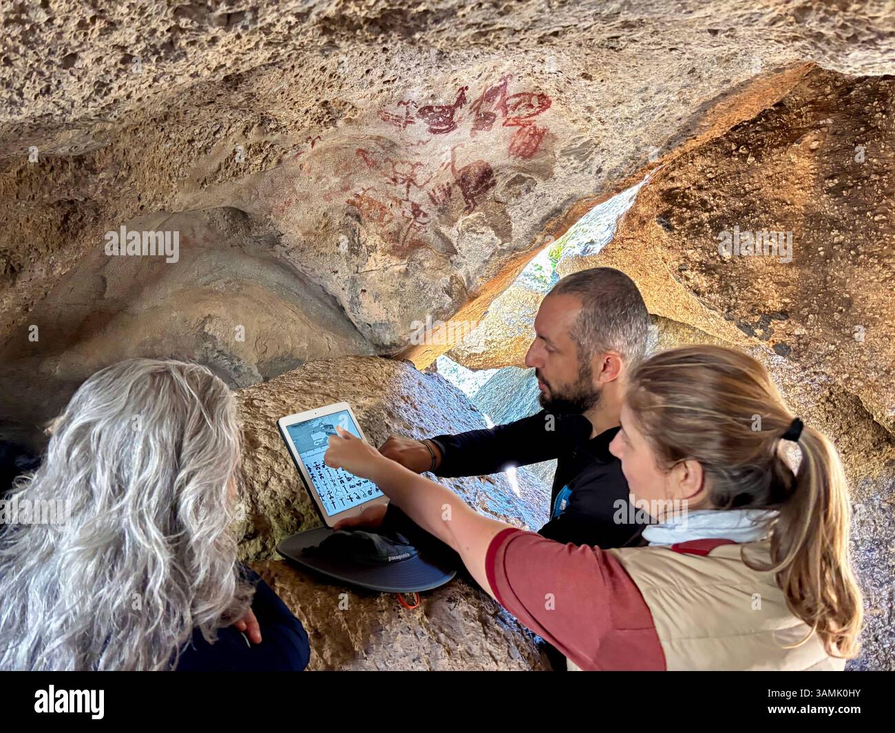 Visitors inspecting the Prehistorical cave paintings in Latmos ...