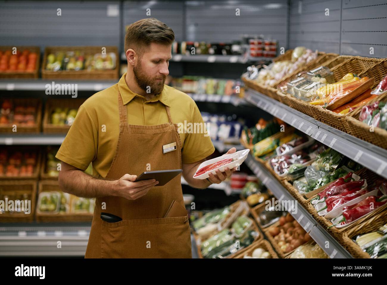 Male grocery store worker checking packaged meat holding digital tablet ...