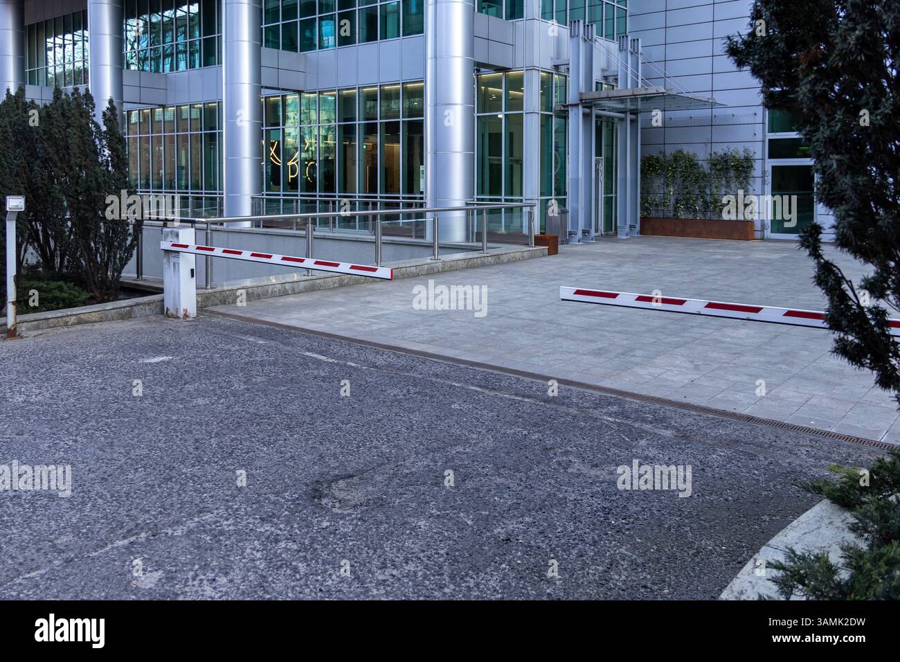 Automated parking access barriers lowered in front of a modern office building with a glass and ...