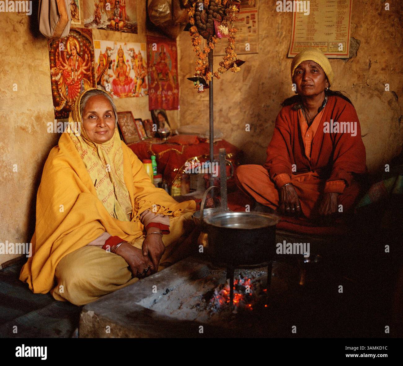 Two women sages warm themselves around their cook fire in Rishikesh ...