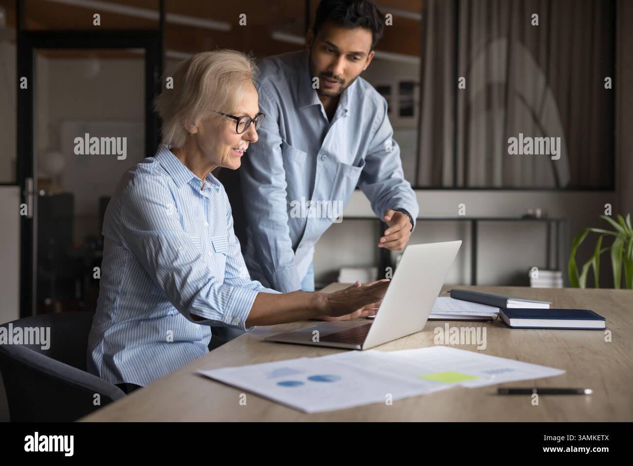 Two diverse colleagues work together using laptop computer Stock Photo ...