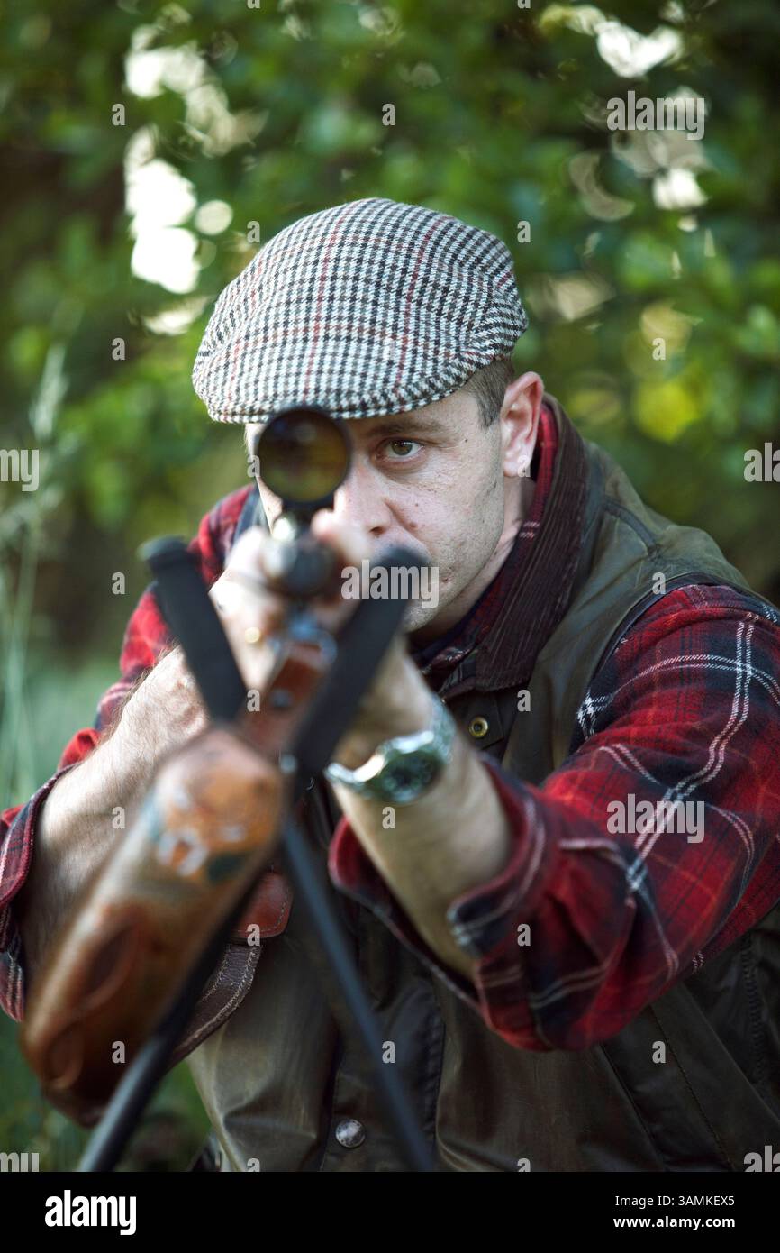 A man looks through the scope of his rifle to line up his shot while ...