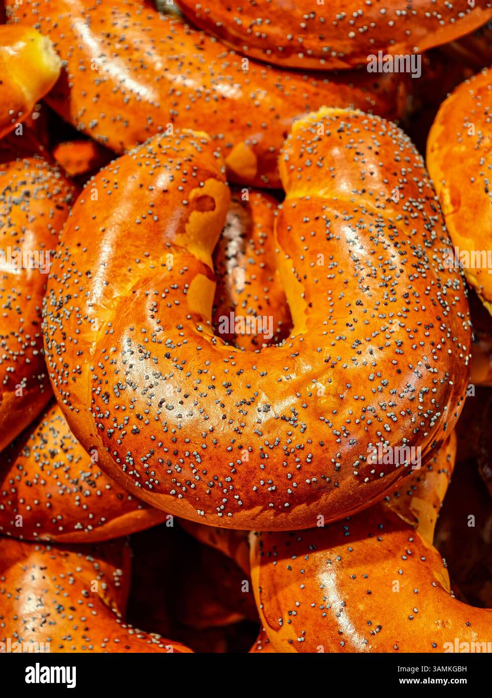 Close-up of freshly baked golden crescent rolls topped with poppy seeds ...