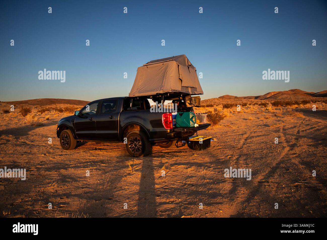 Truck with rooftop tent parked in desert during golden hour Stock Photo ...