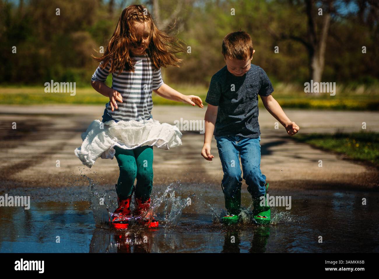Two children jumping in a rain puddle wear rain boots Stock Photo - Alamy