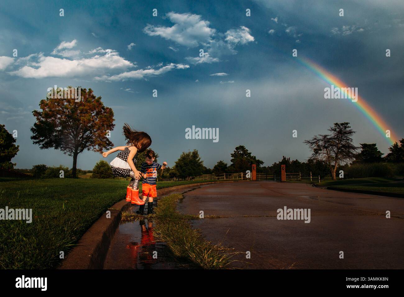 Girl in mid-air jumping in puddle with rainbow Stock Photo - Alamy