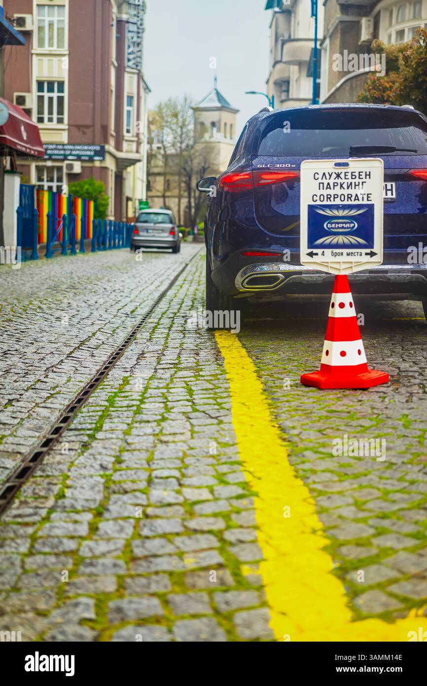 Parking regulation sign near parked blue car on cobblestone street in ...