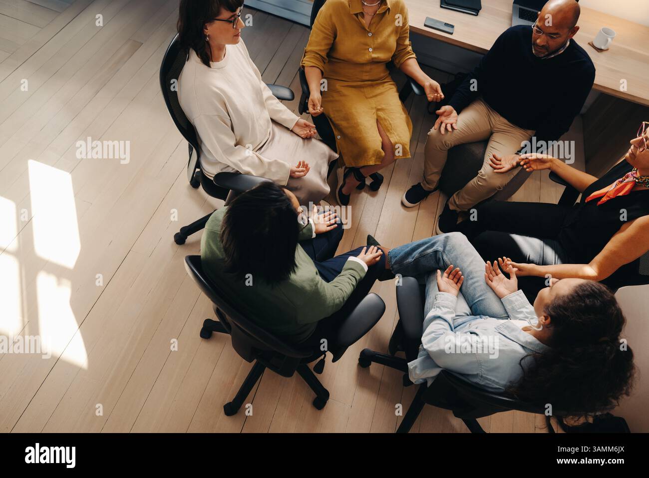 A group of colleagues is sitting together in an office participating in ...