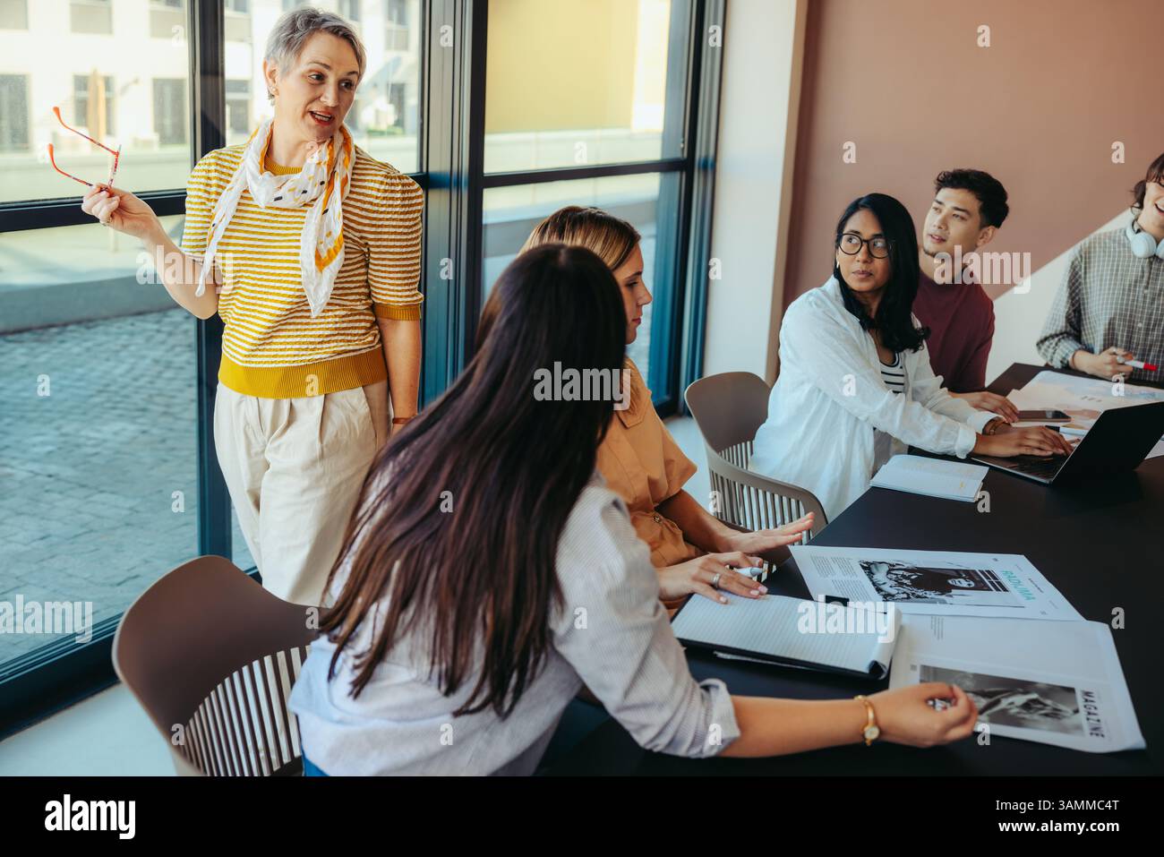 College lecturer leads a discussion with engaged students in a city ...