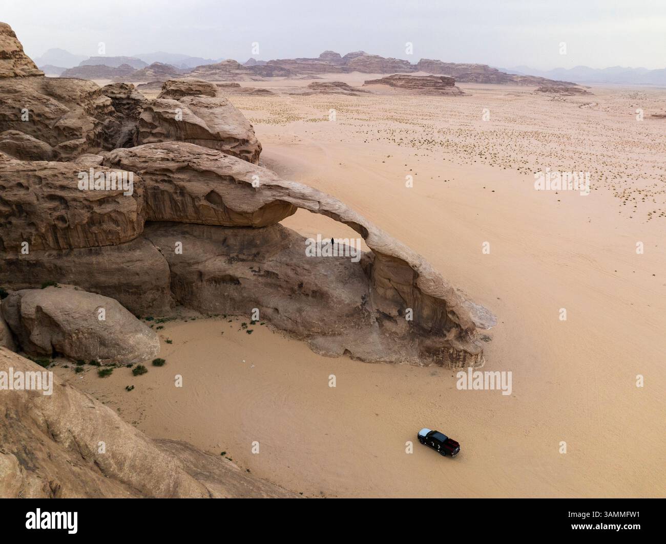 Aerial view of vast sandy desert with rugged rock formations and an off ...