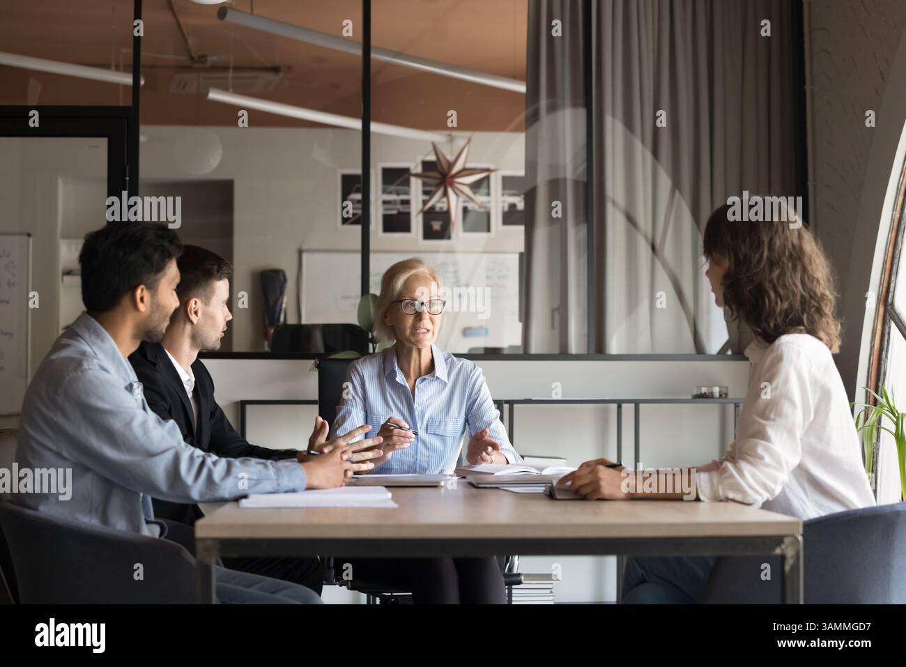 Mid-aged business woman speaking at international team meeting Stock ...