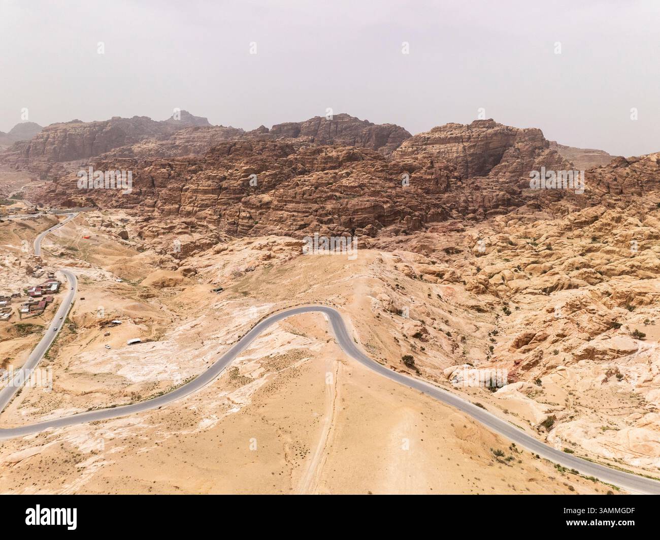 Aerial view of rugged desert landscape with a winding road and barren ...