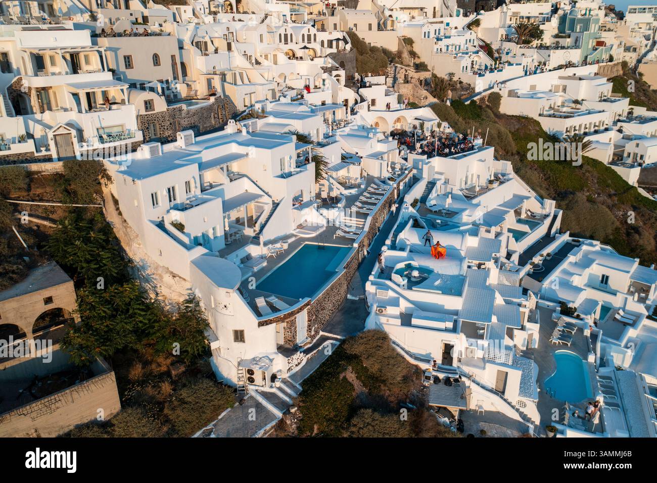 Aerial view of picturesque white buildings and blue pools with terraces ...