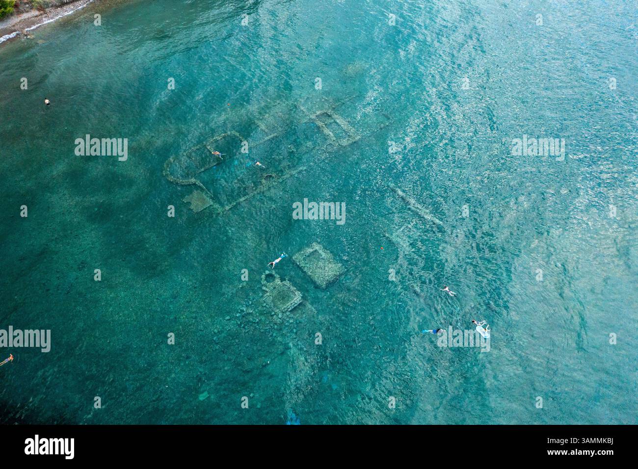 Aerial view of underwater ruins in clear blue sea with swimmers, Archea ...