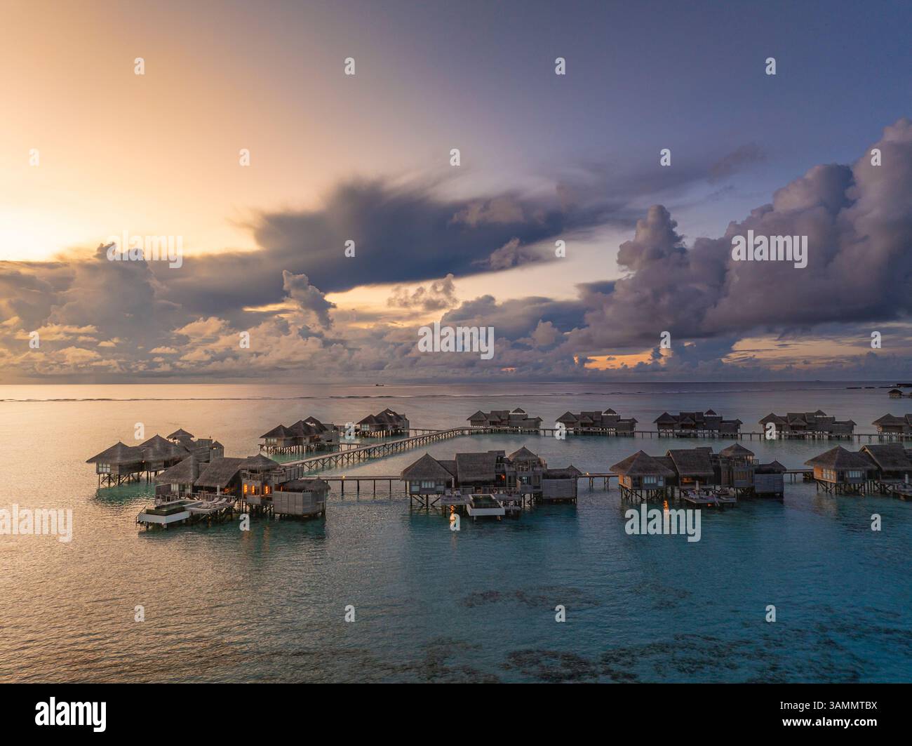 Aerial view of overwater bungalows at sunset in a tropical paradise ...