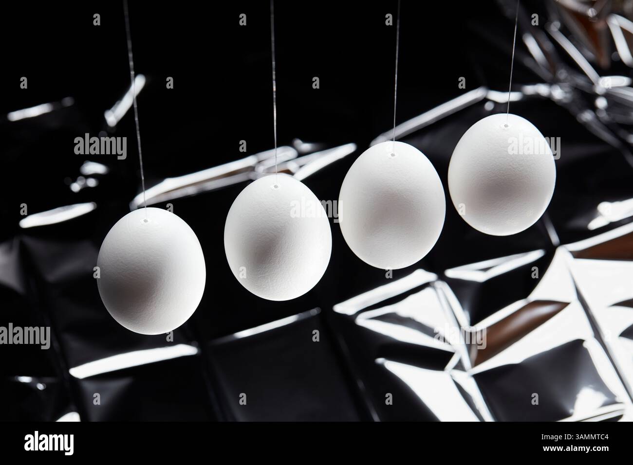 Four white eggs hanging in a slightly staggered horizontal line from ...