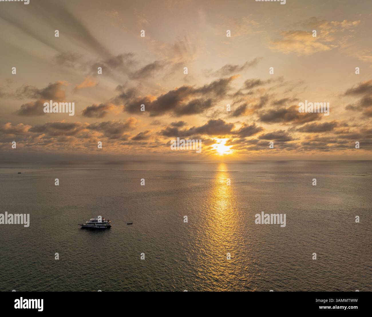 Aerial view of serene sunset over the ocean with a boat reflecting on ...
