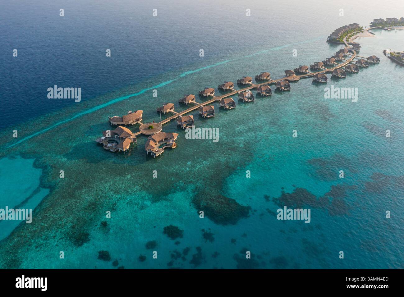 Aerial view of a luxury resort bungalows along the reef barrier on Raa Atoll, Maldives ...