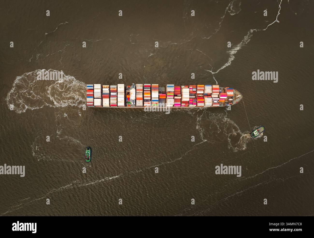 Tug boats push and pull a huge container vessel Stock Photo - Alamy