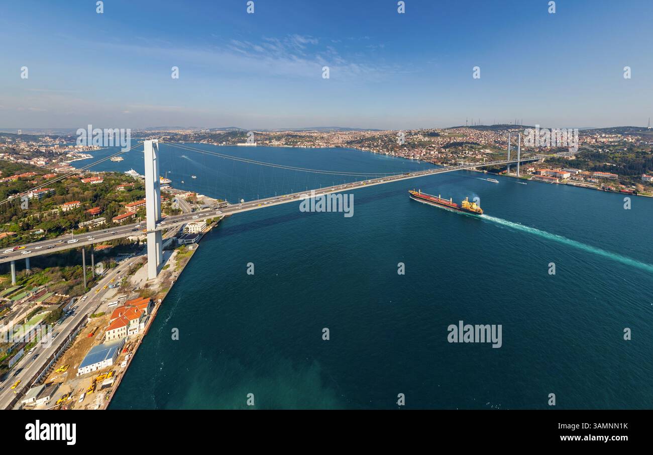 Aerial view of a shipping boat crossing under Bosphorus bridge ...