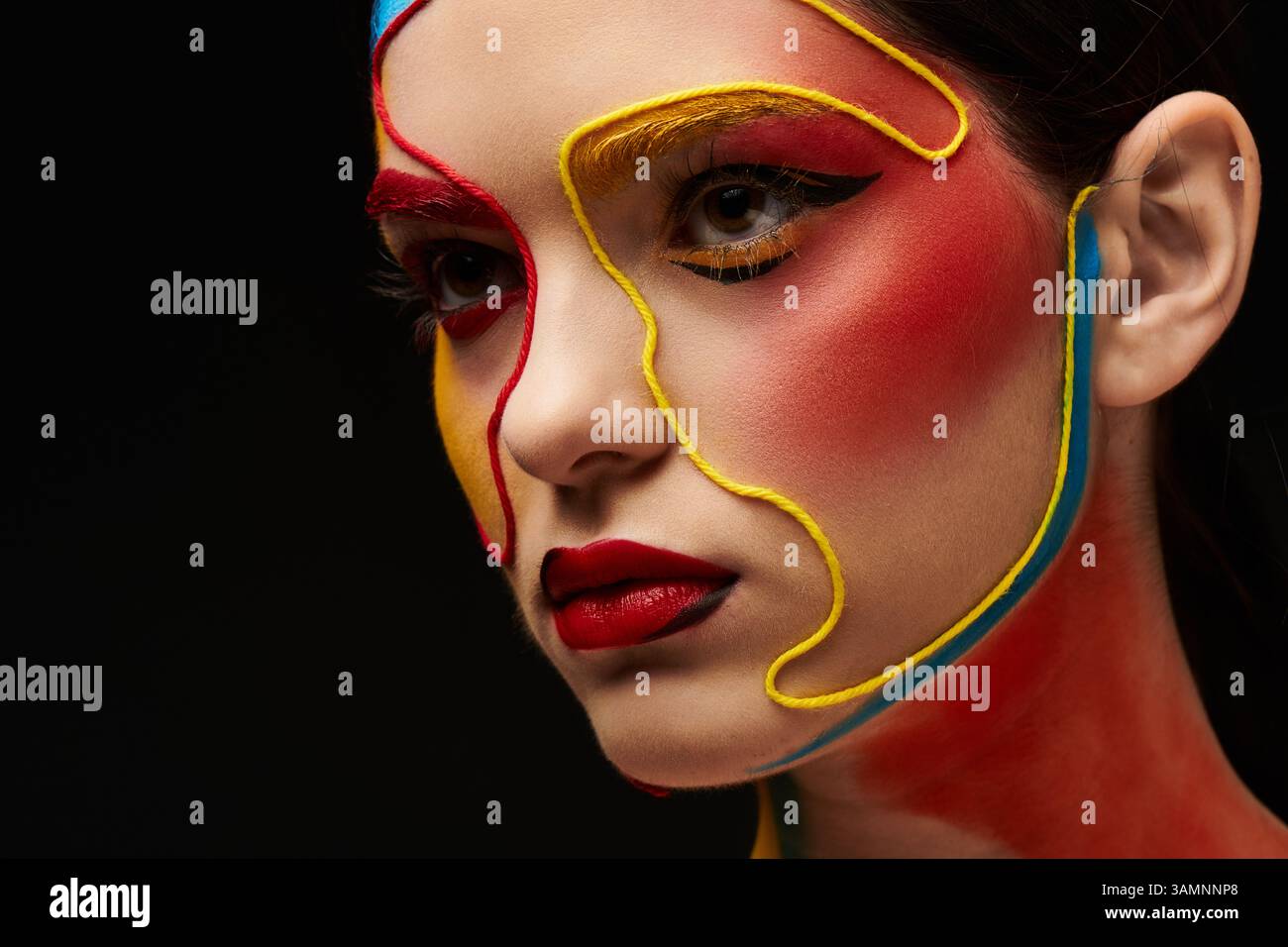 A young woman displays stunning face art with vibrant colors and ...
