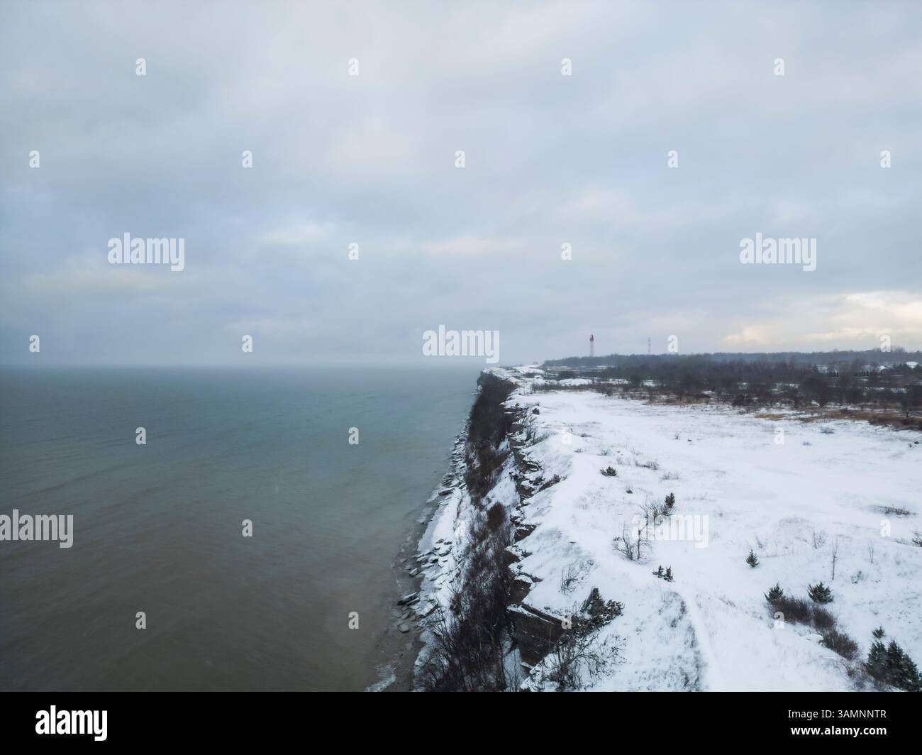 Aerial view of snowy cliffs along the rugged coast with tranquil sea ...