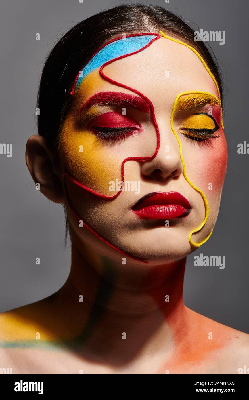 A young woman displays vibrant face art with bold colors and stylish ...