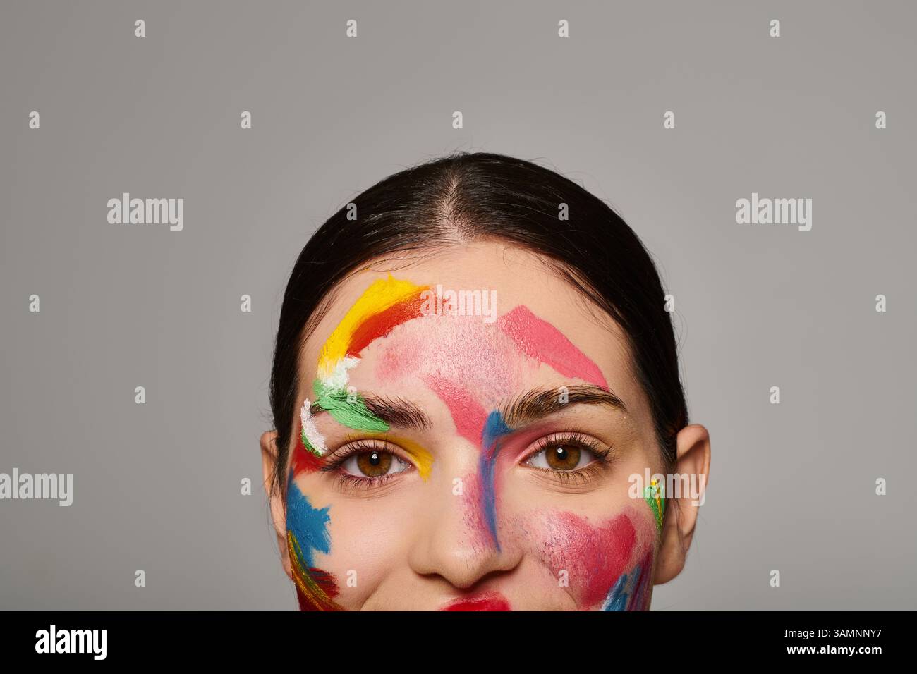 A young woman displays vibrant face art, radiating creativity and joy ...