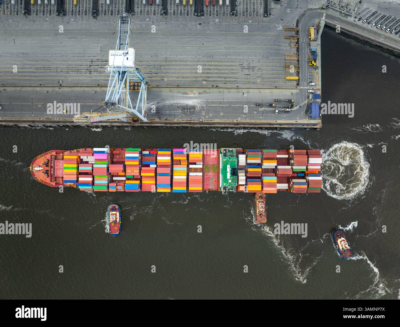 Tug boats push and pull a huge container vessel Stock Photo - Alamy
