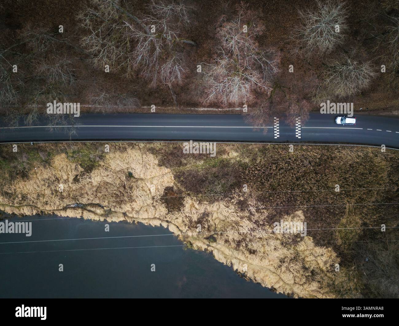 Aerial view of winding road alongside a serene river and tranquil ...