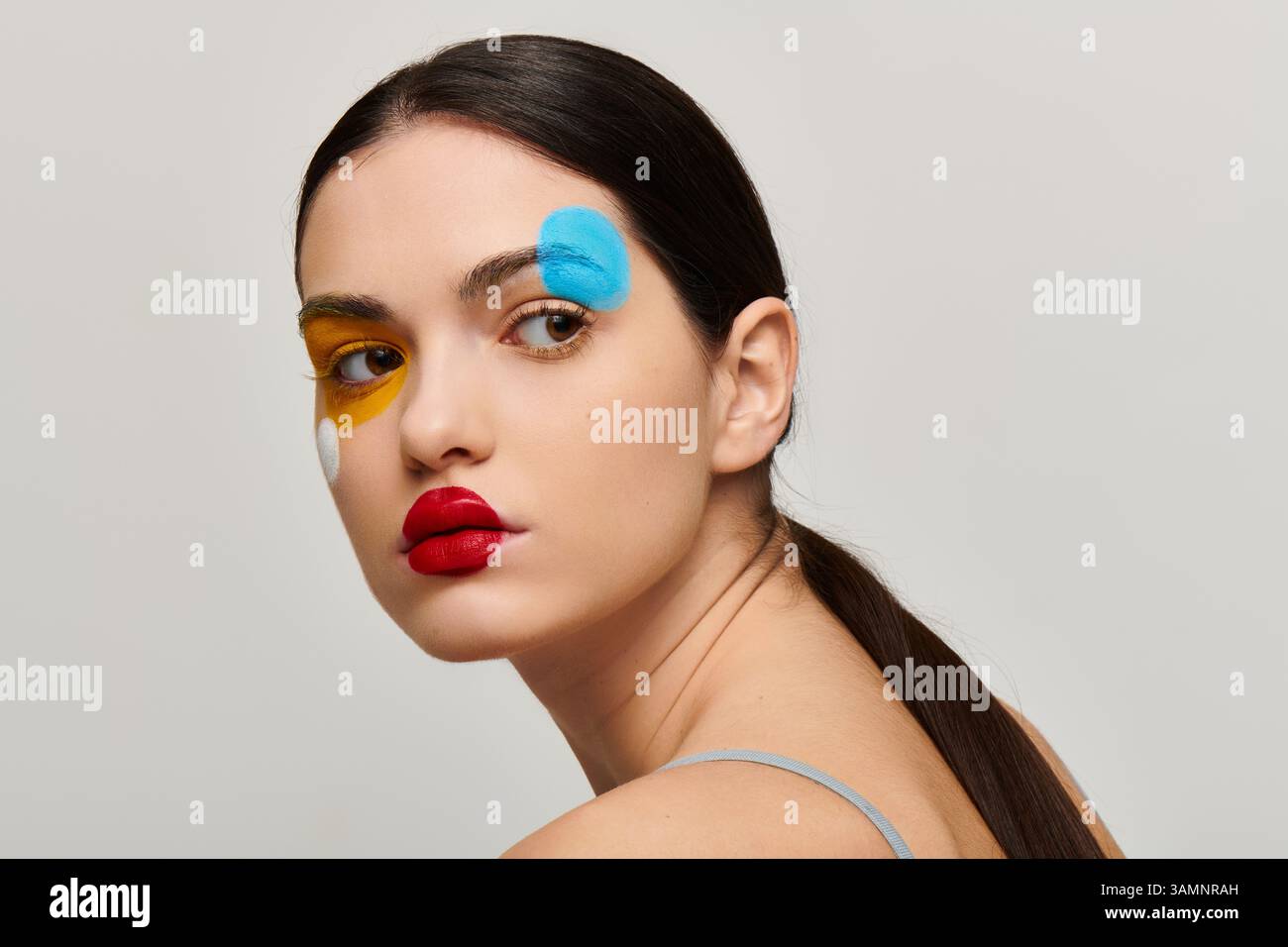 A young woman displays bold, colorful face art on her cheeks, embodying ...